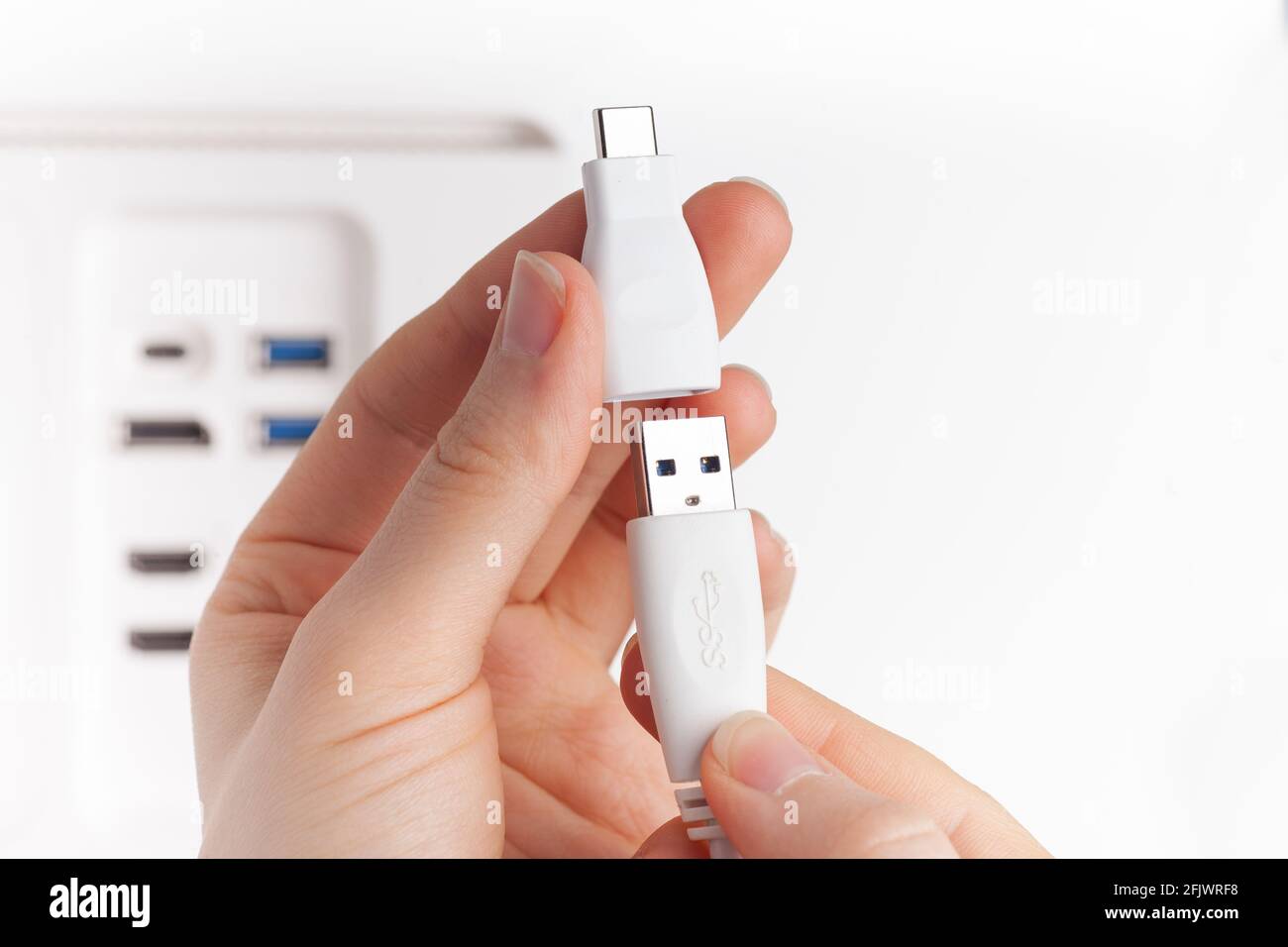 Close-up of the cable connection by hand to type-c port adapter. White ...