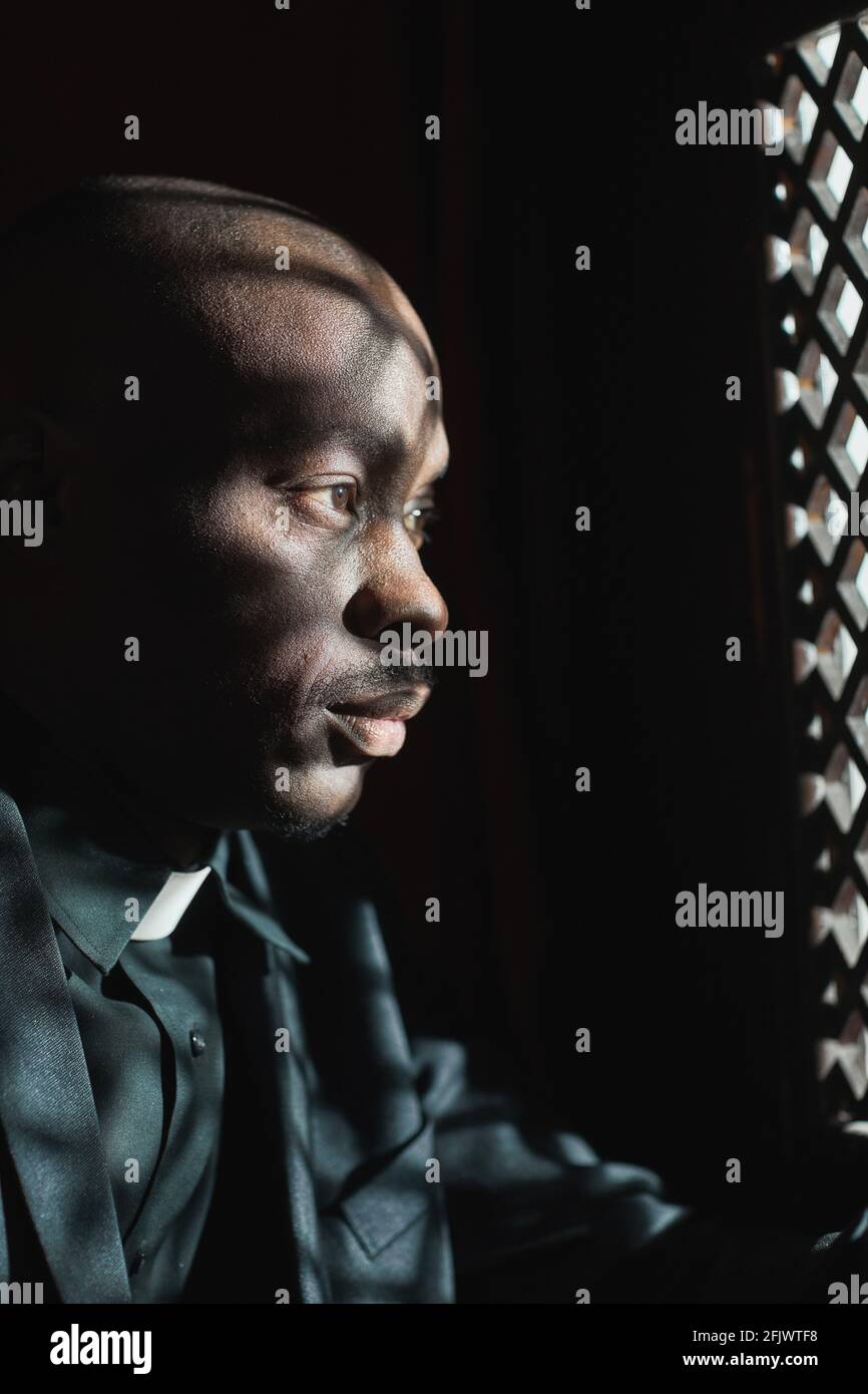 African man sitting in confessional and listening to confession in the ...