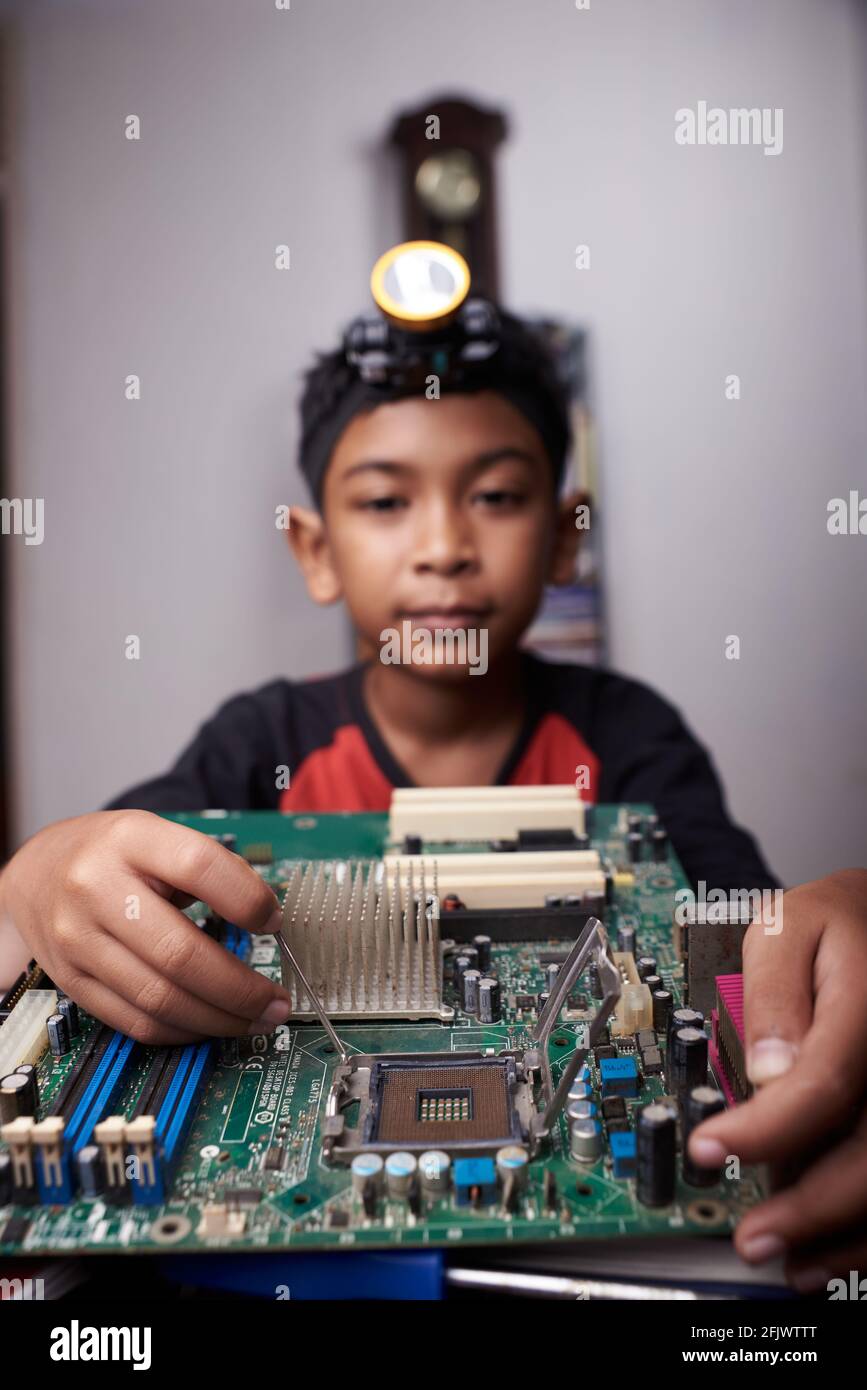 Little boy holding the motherboard, studying computer component at home ...