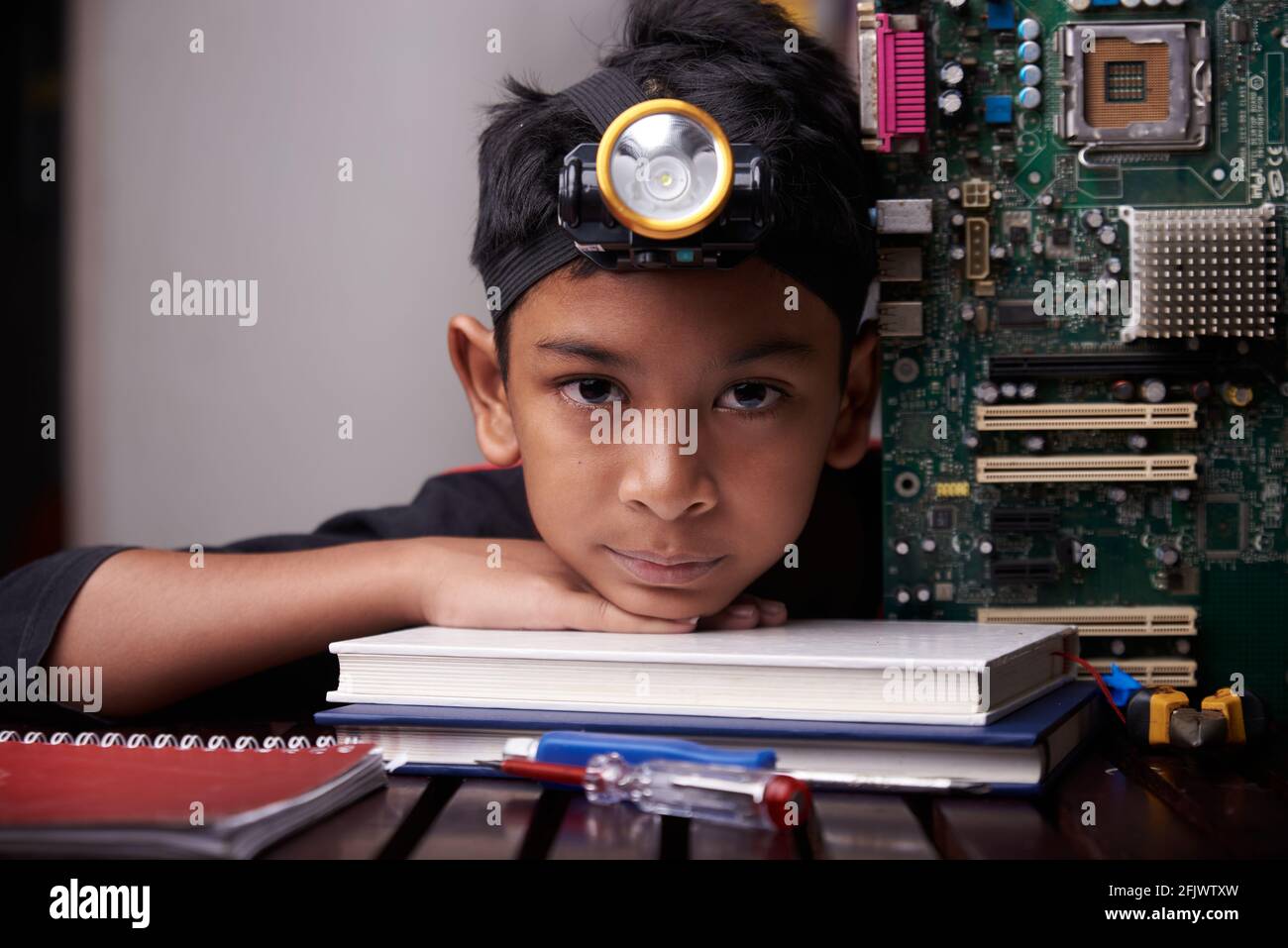 Little boy holding the motherboard, studying computer component at home ...
