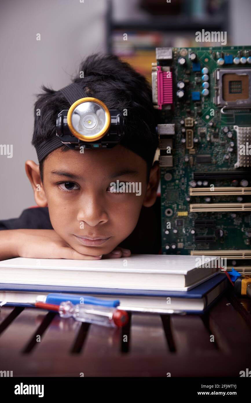 Little boy holding the motherboard, studying computer component at home ...