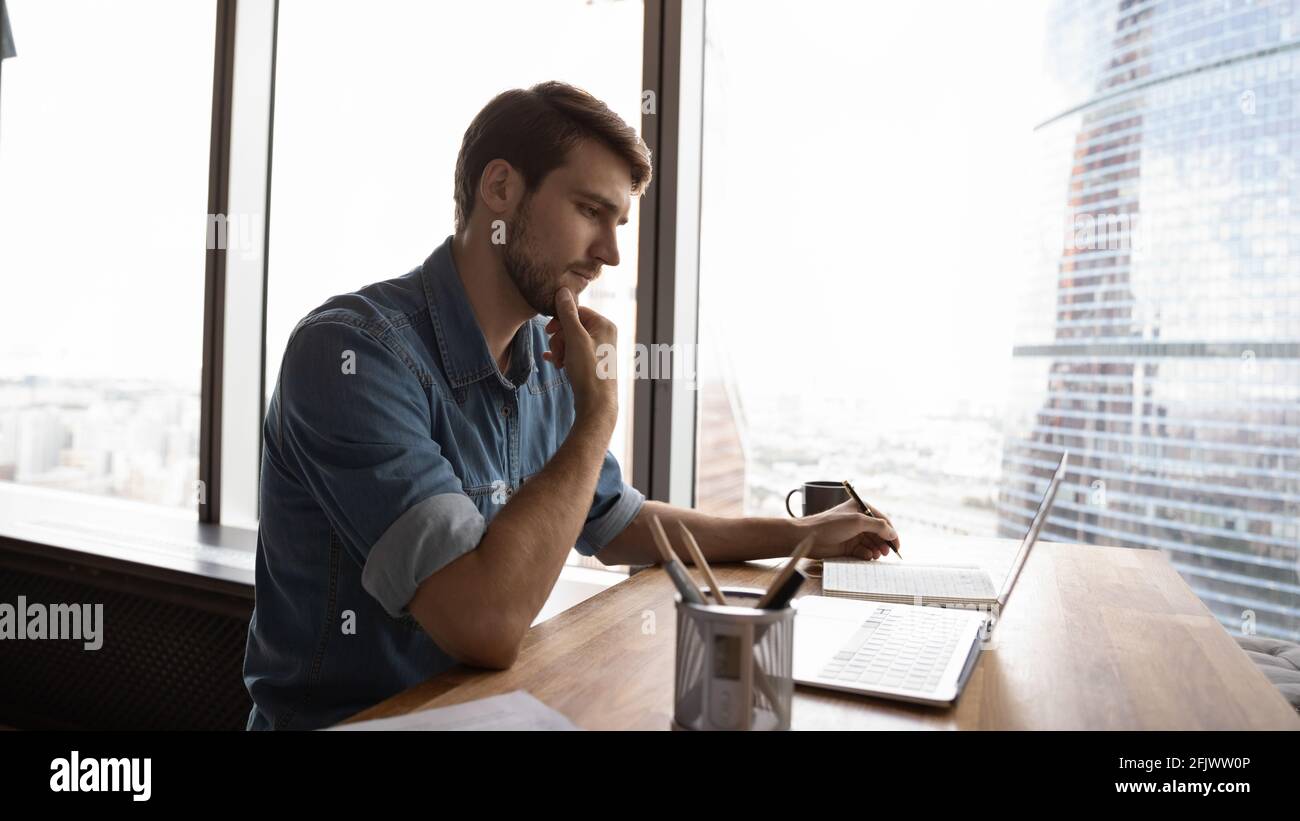 Serious Caucasian man work on laptop thinking Stock Photo - Alamy