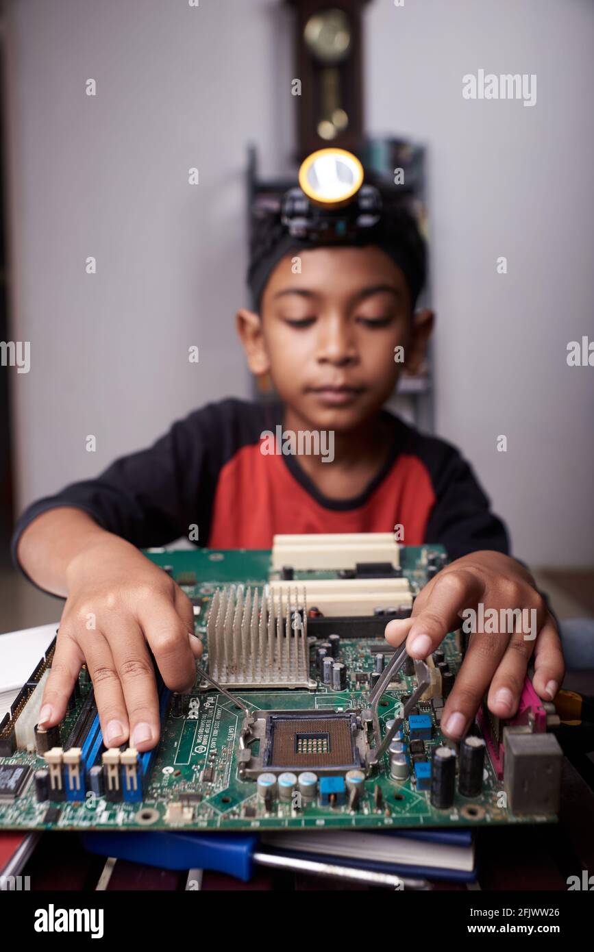 Little boy holding the motherboard, studying computer component at home ...