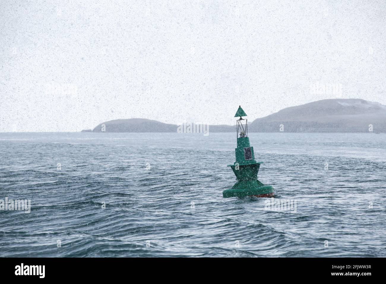 Green buoy with cone shaped topmark on a snowy day. Navigation ...