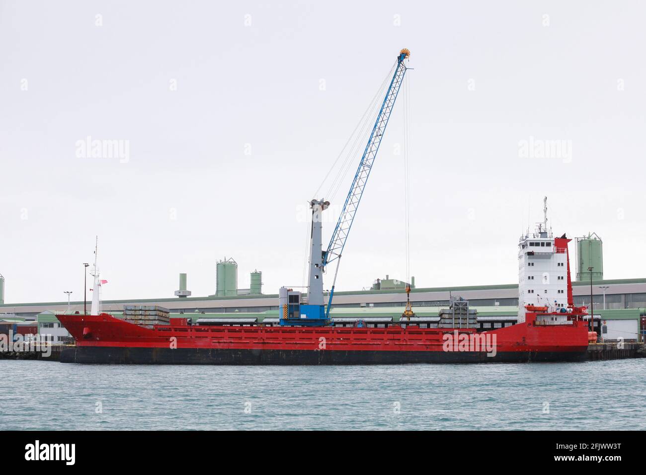Cargo ship with red hull is loading in port of Reykjavik an a cloudy ...