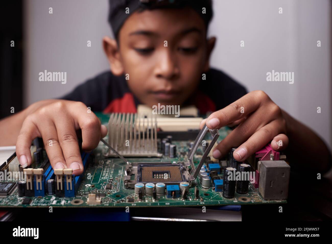 Little boy holding the motherboard, studying computer component at home ...