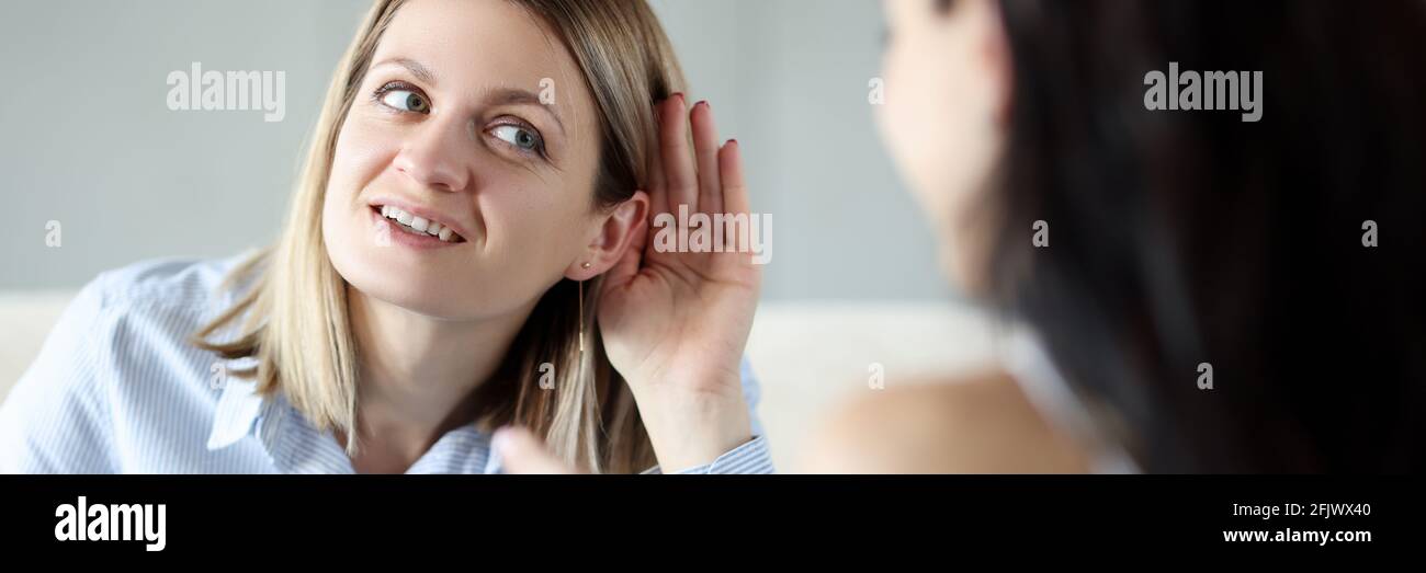 Young woman holding her ear and talking to friend Stock Photo - Alamy