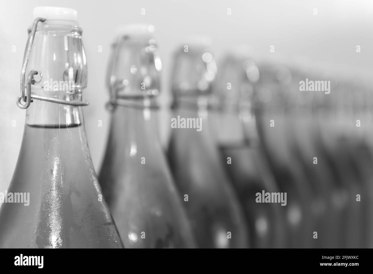 Black and white photo of a row of flip top bottles of home made cider ...