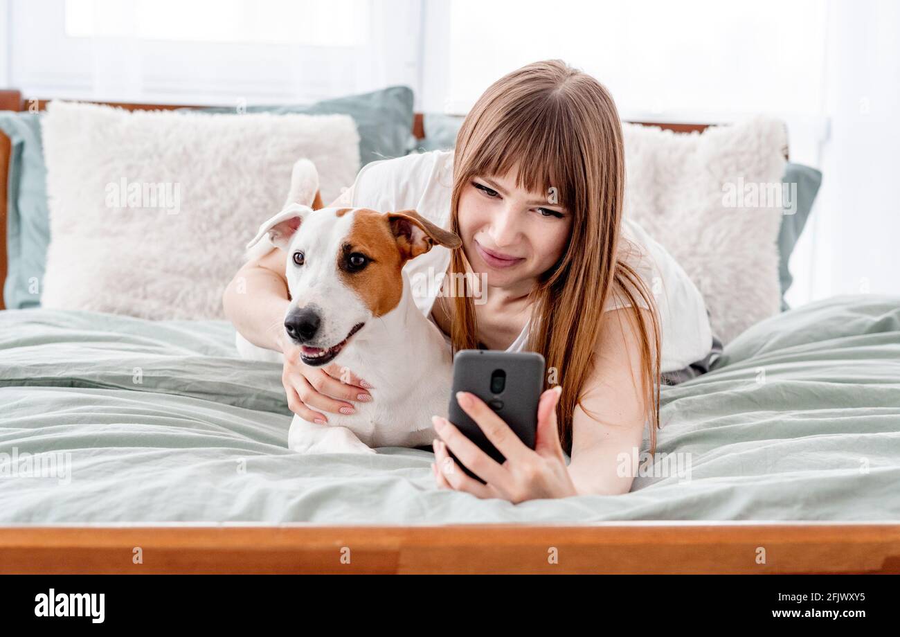Girl with dog and smartphone in the bed Stock Photo - Alamy