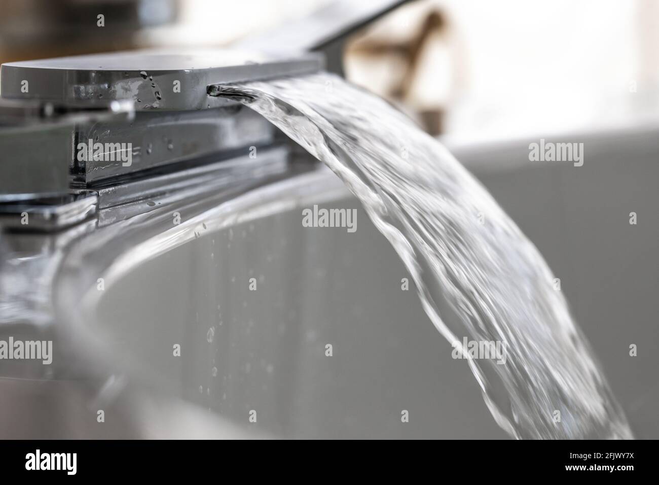 Spout running water from wide bath tube faucet into a hot Jacuzzi Stock ...