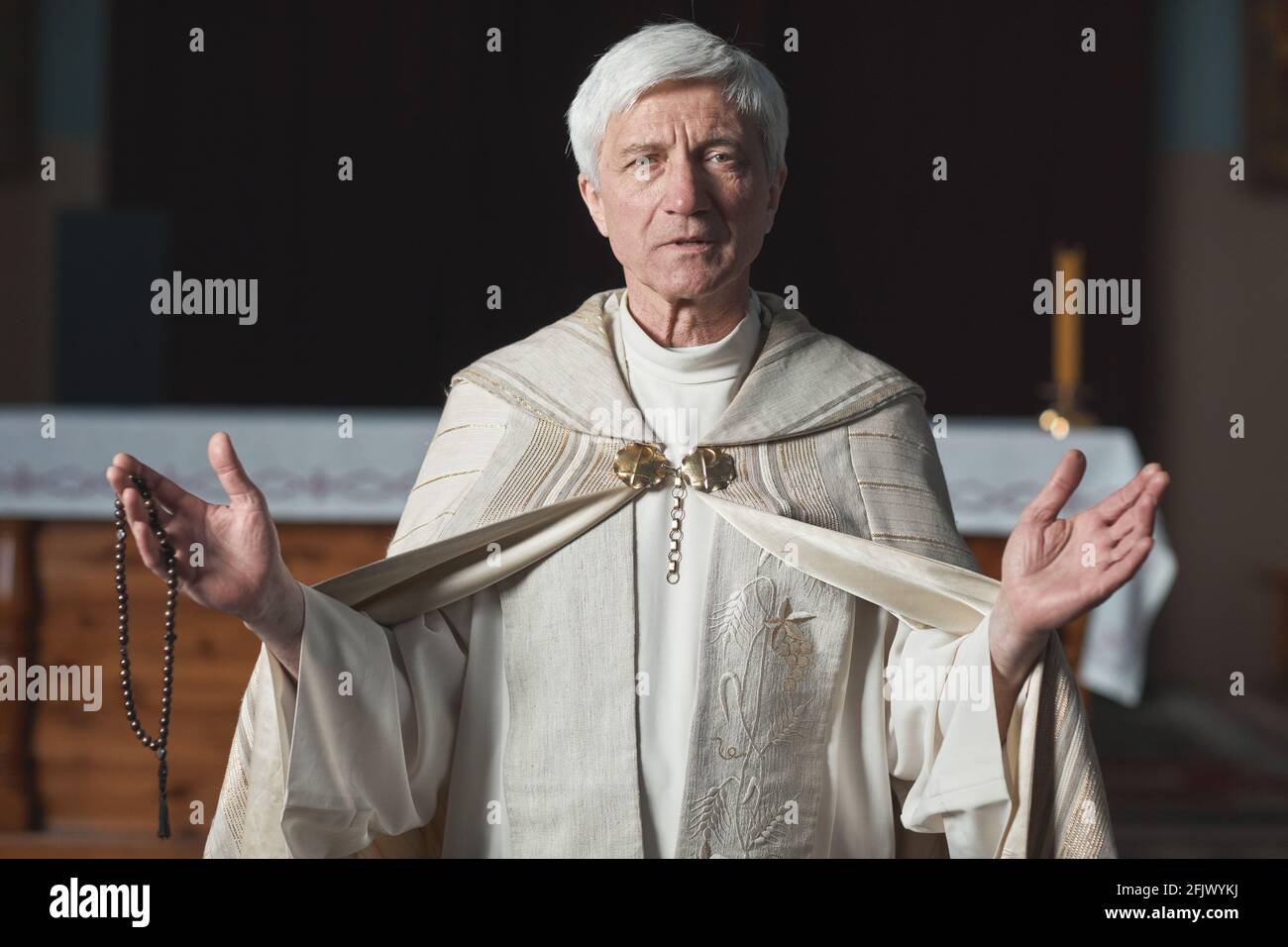 Portrait of senior priest in formal costume looking at camera and ...