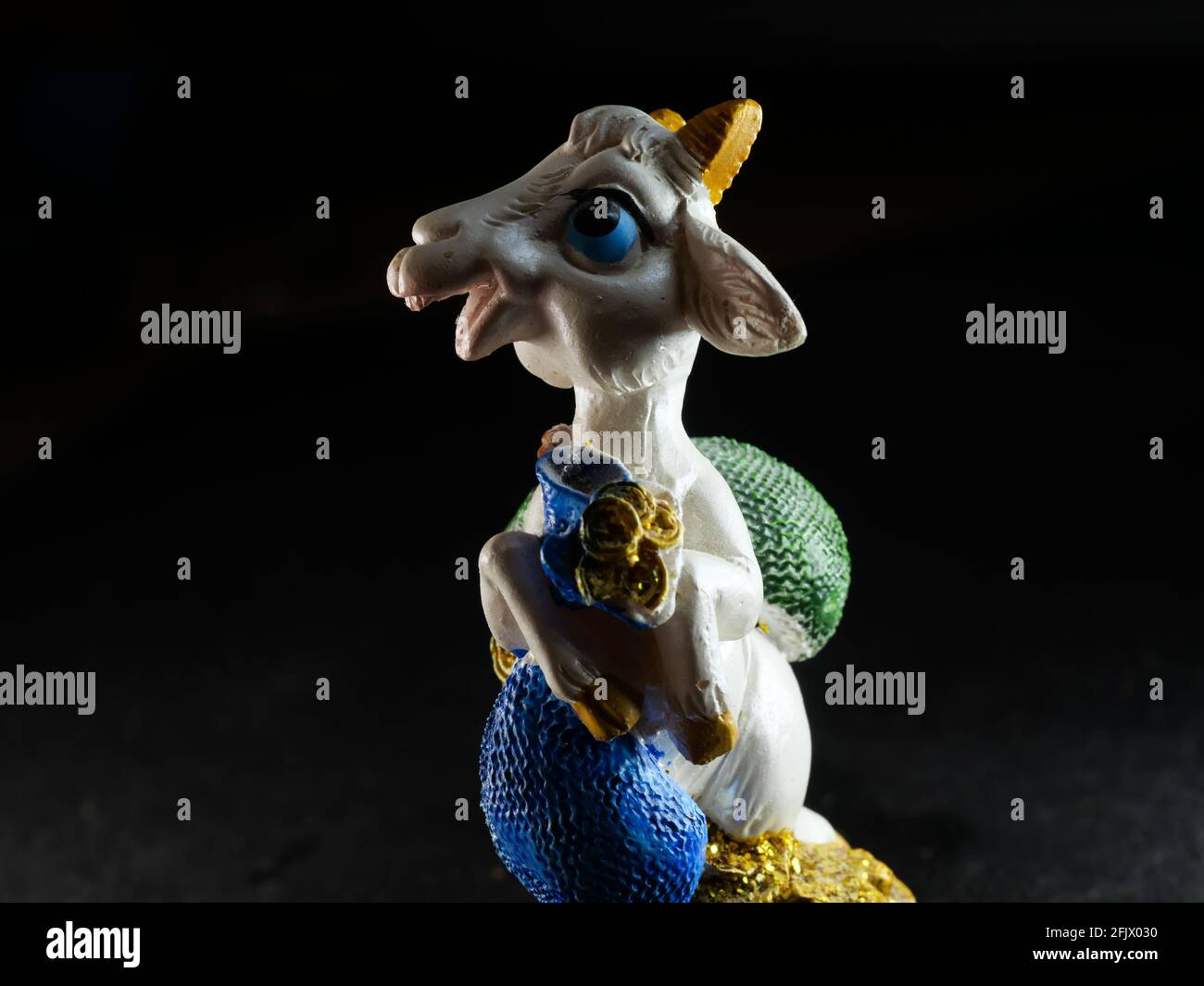 Statue of a goat carrying gold symbolizing wealth isolated on the black ...