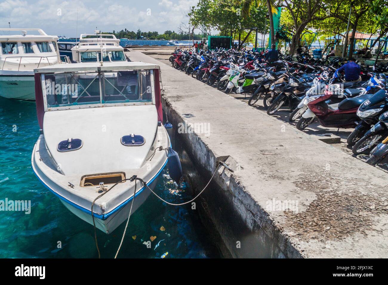 MALE, MALDIVES - JULY 11, 2016: Boats anchored next to motorcycle ...