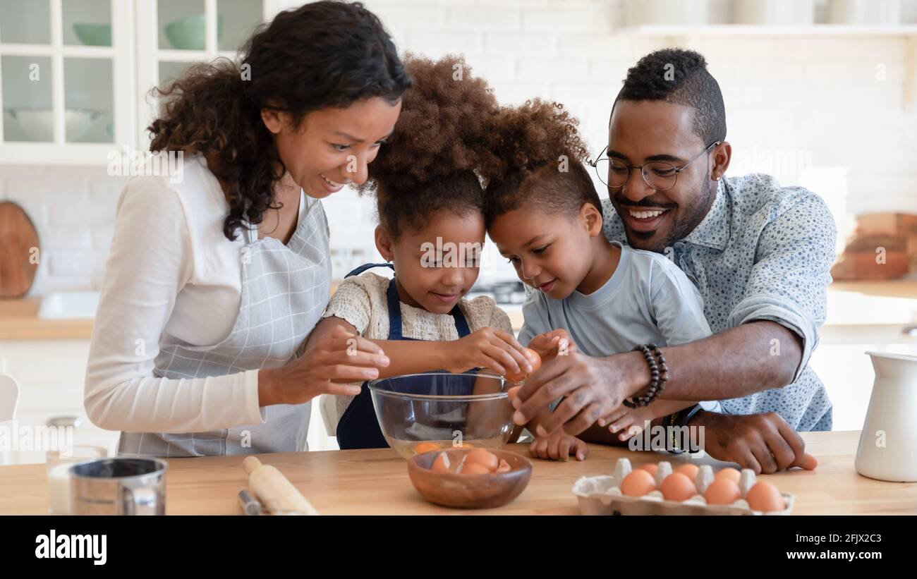 Happy African American parents and kids baking together in kitchen ...