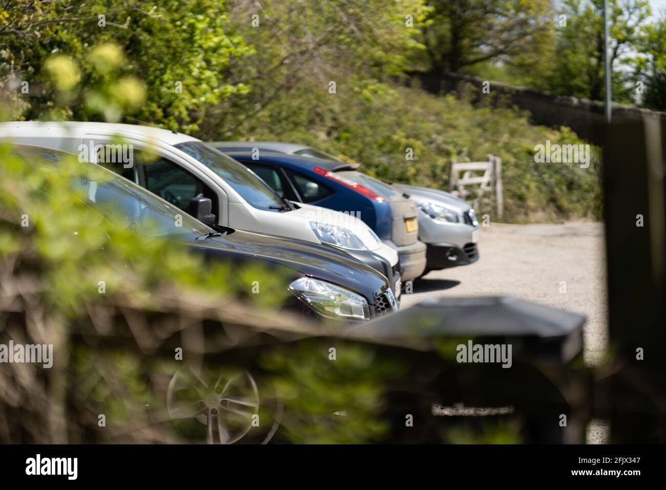 group of cars parked in a gravel country side car park on a bright ...