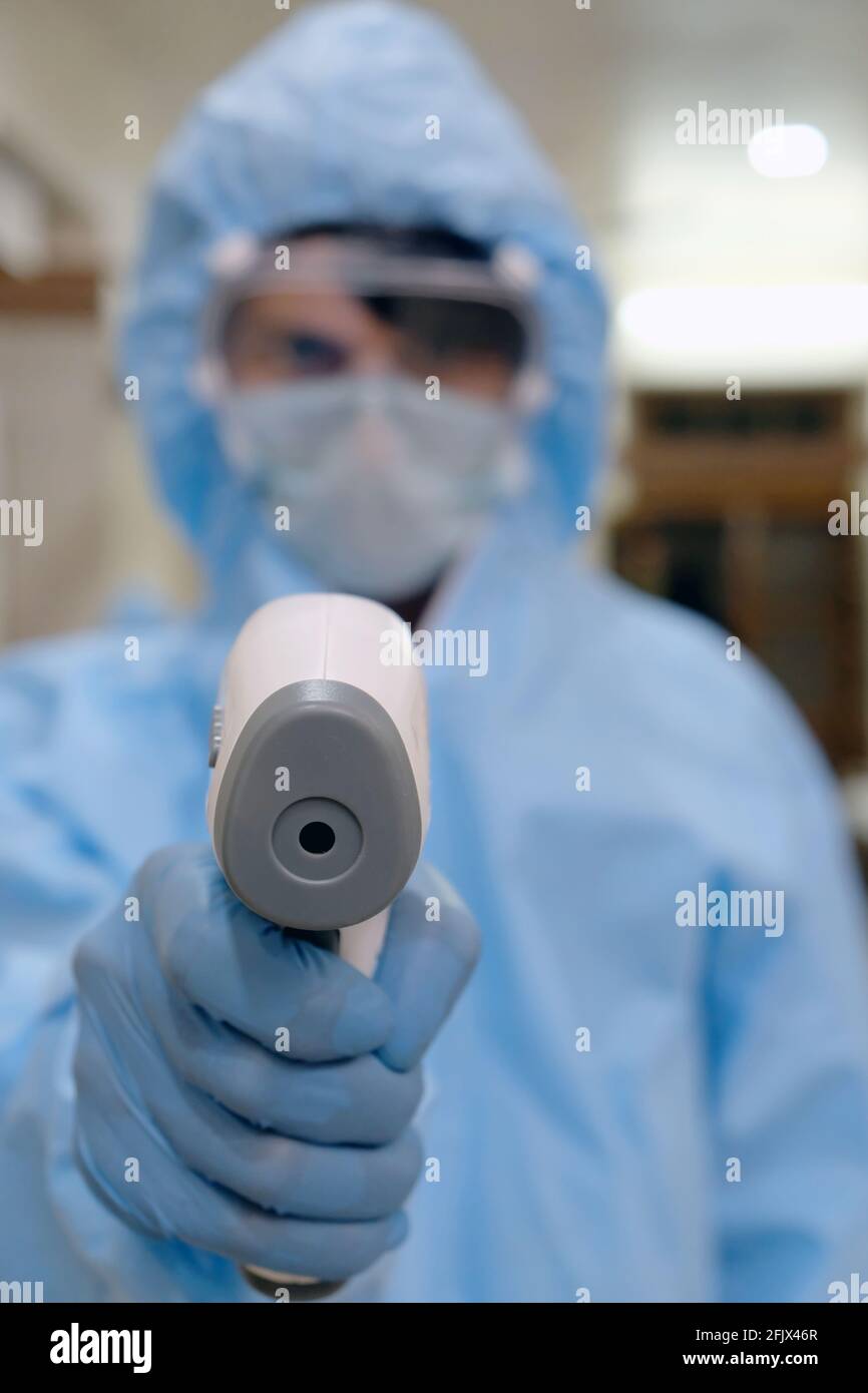 Vertical shot of a South Asian doctor in full medical gear pointing a ...