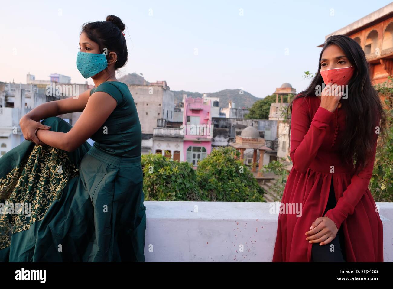 Indian young females in national costumes and face masks sitting ...