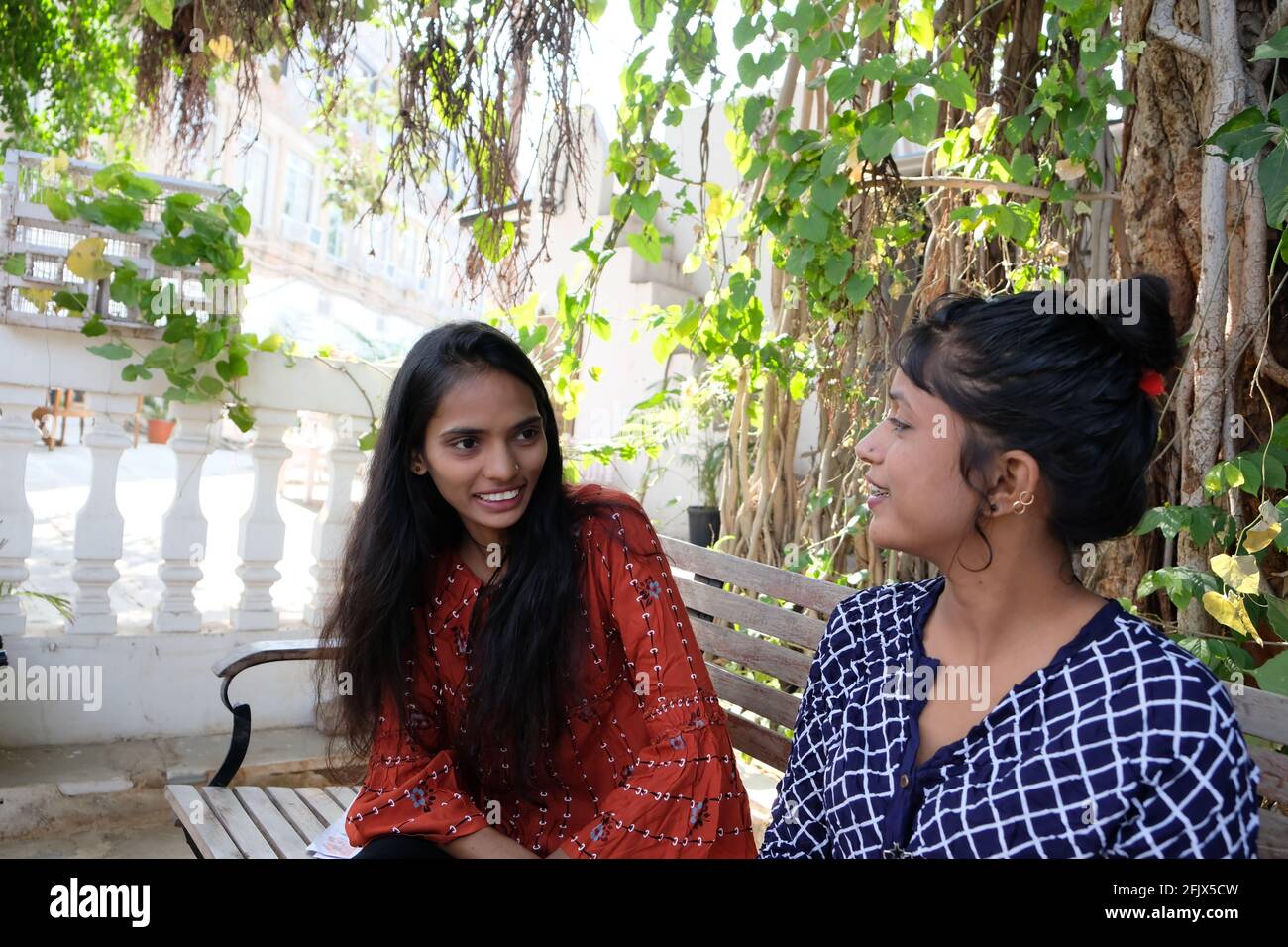 Indian female friends talking to each other sitting on a bench Stock ...