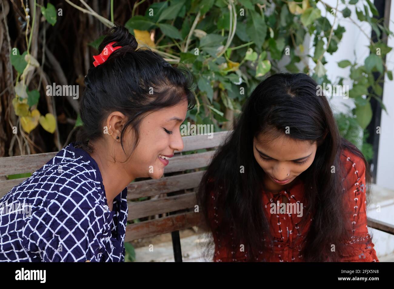 Indian female friends talking to each other sitting on a bench Stock ...