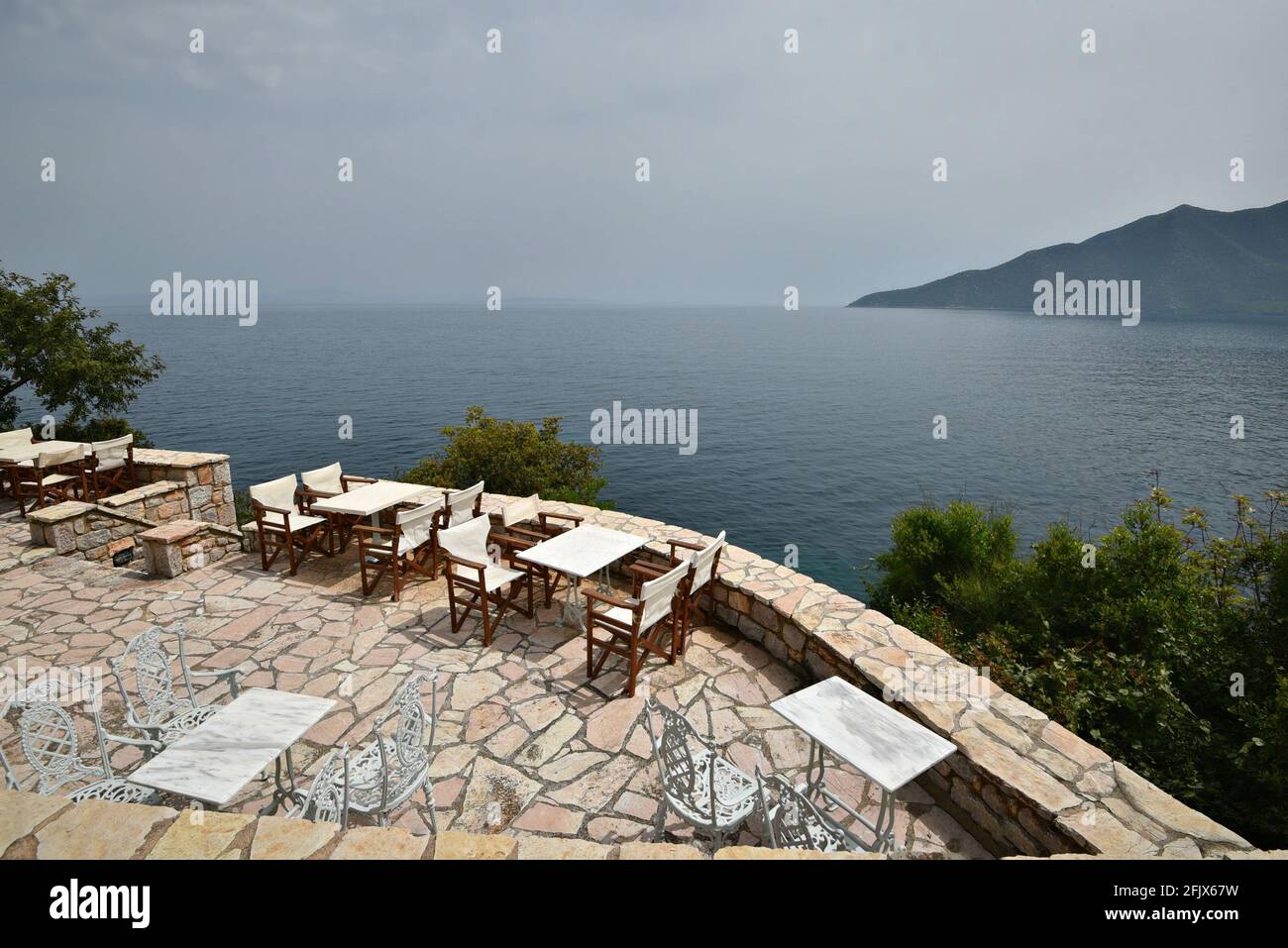 Stone built patio with teak chairs and tables overlooking the Myrtoan ...