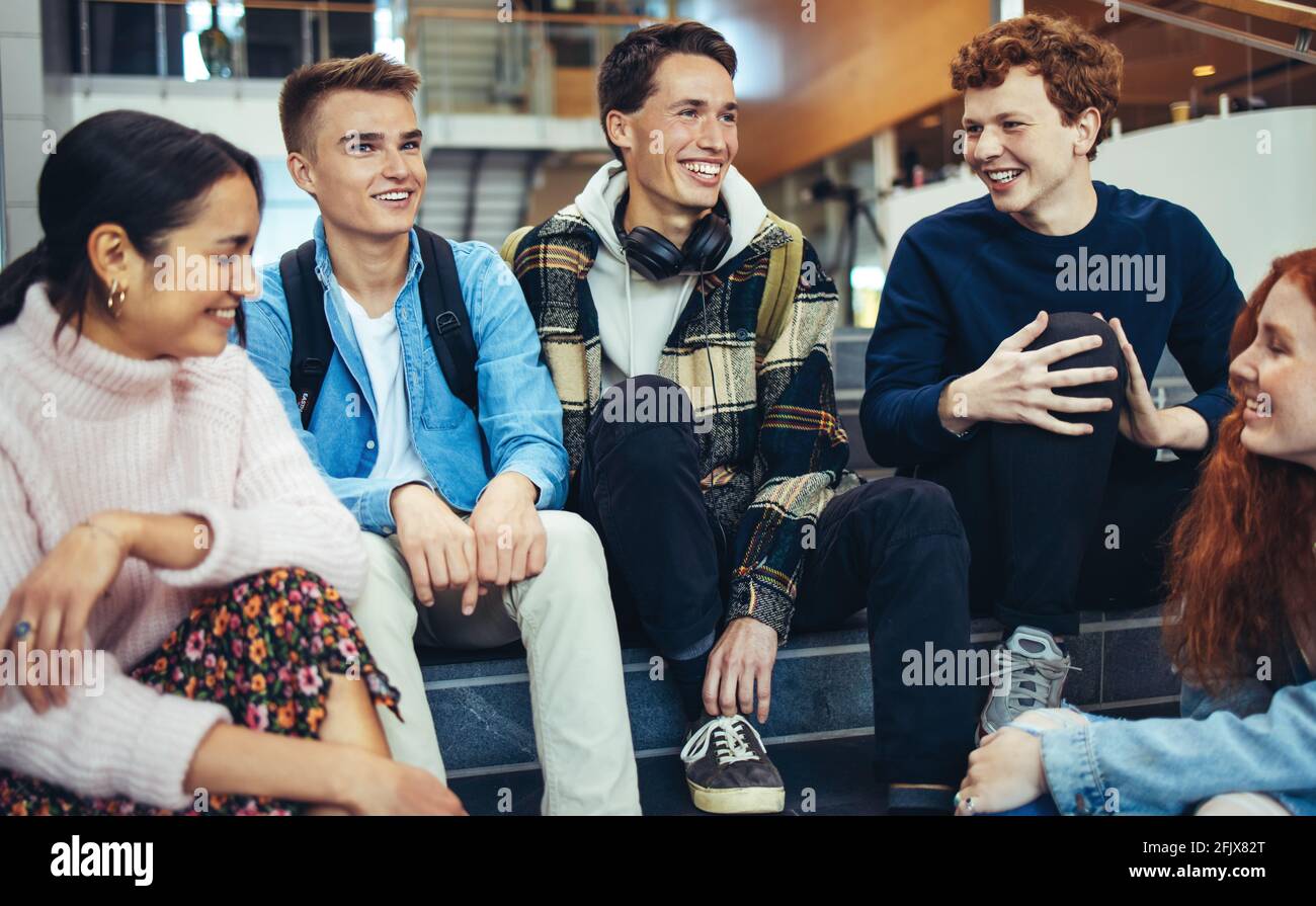 High school group after lecture. Group of teenagers sitting on steps in ...