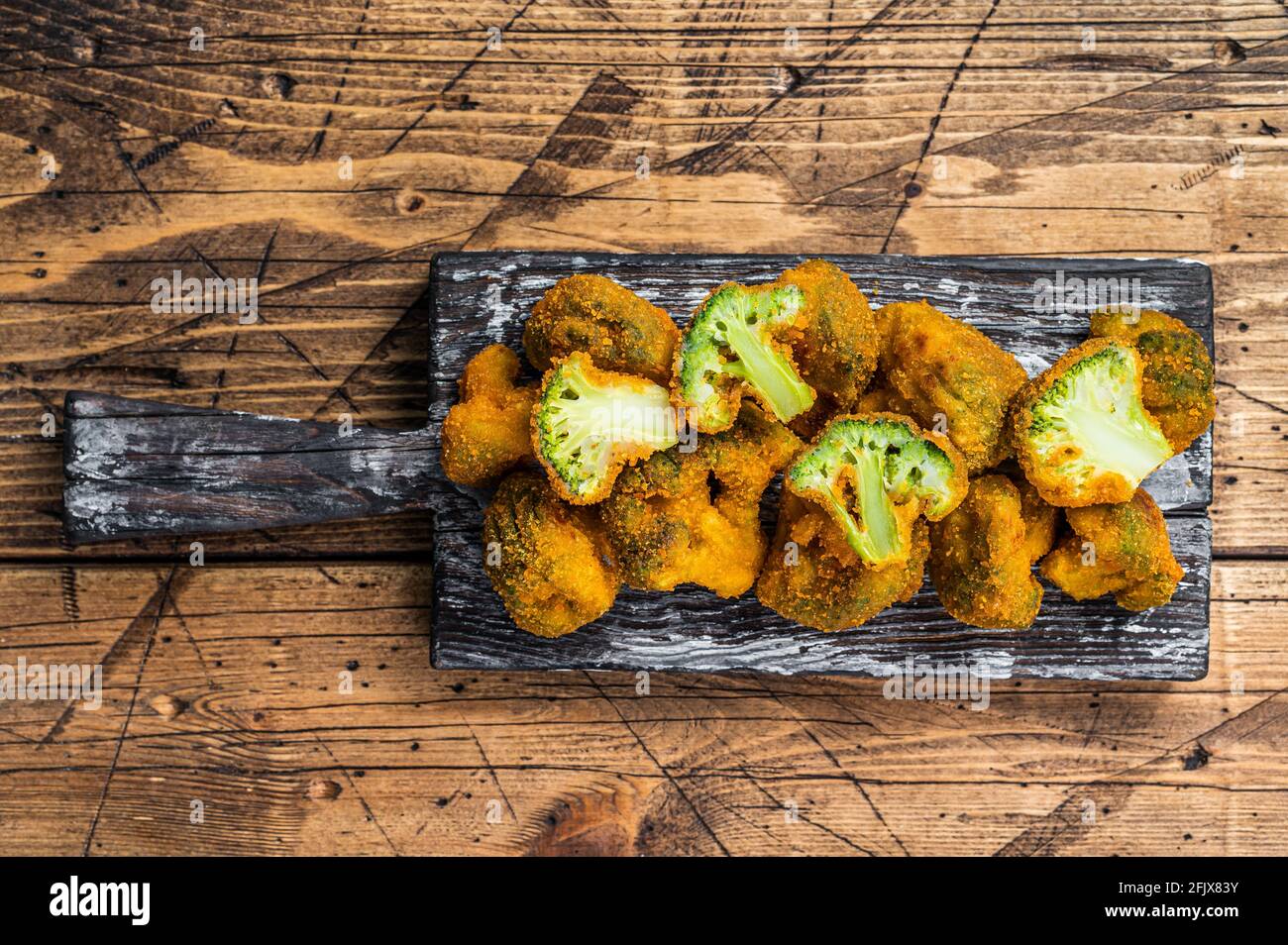 Baked Breaded broccoli on a wooden board with herbs. White wooden ...