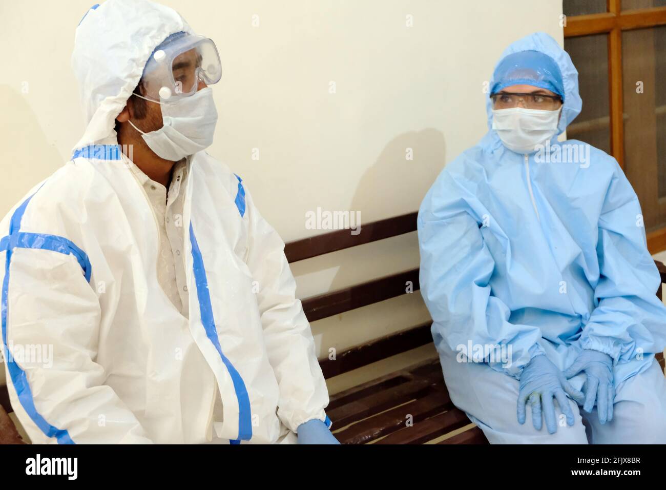 Medical personnel in protective costumes sitting in the hospital during ...