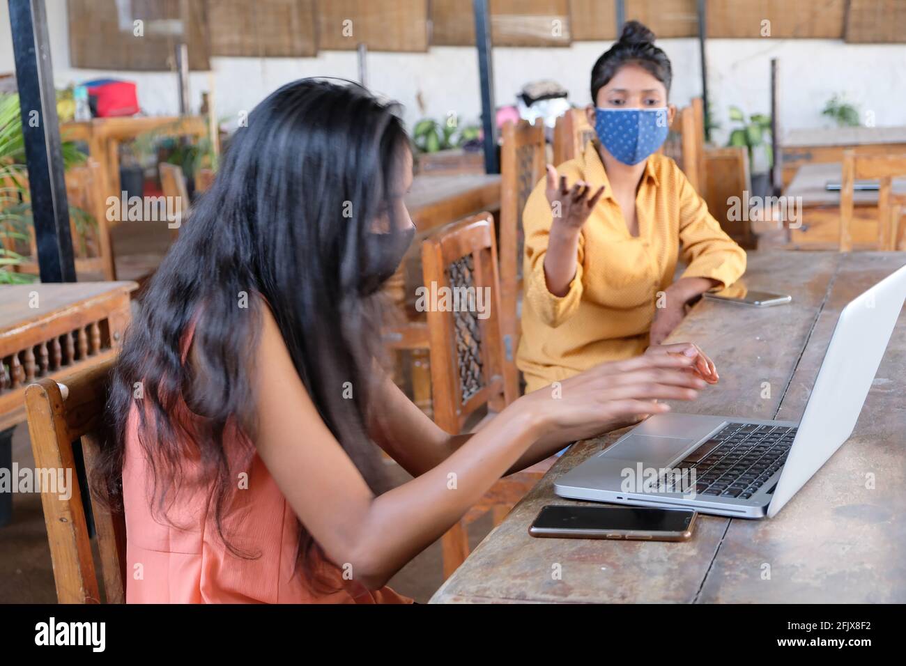 Indian females in face masks communicating keeping social distance ...