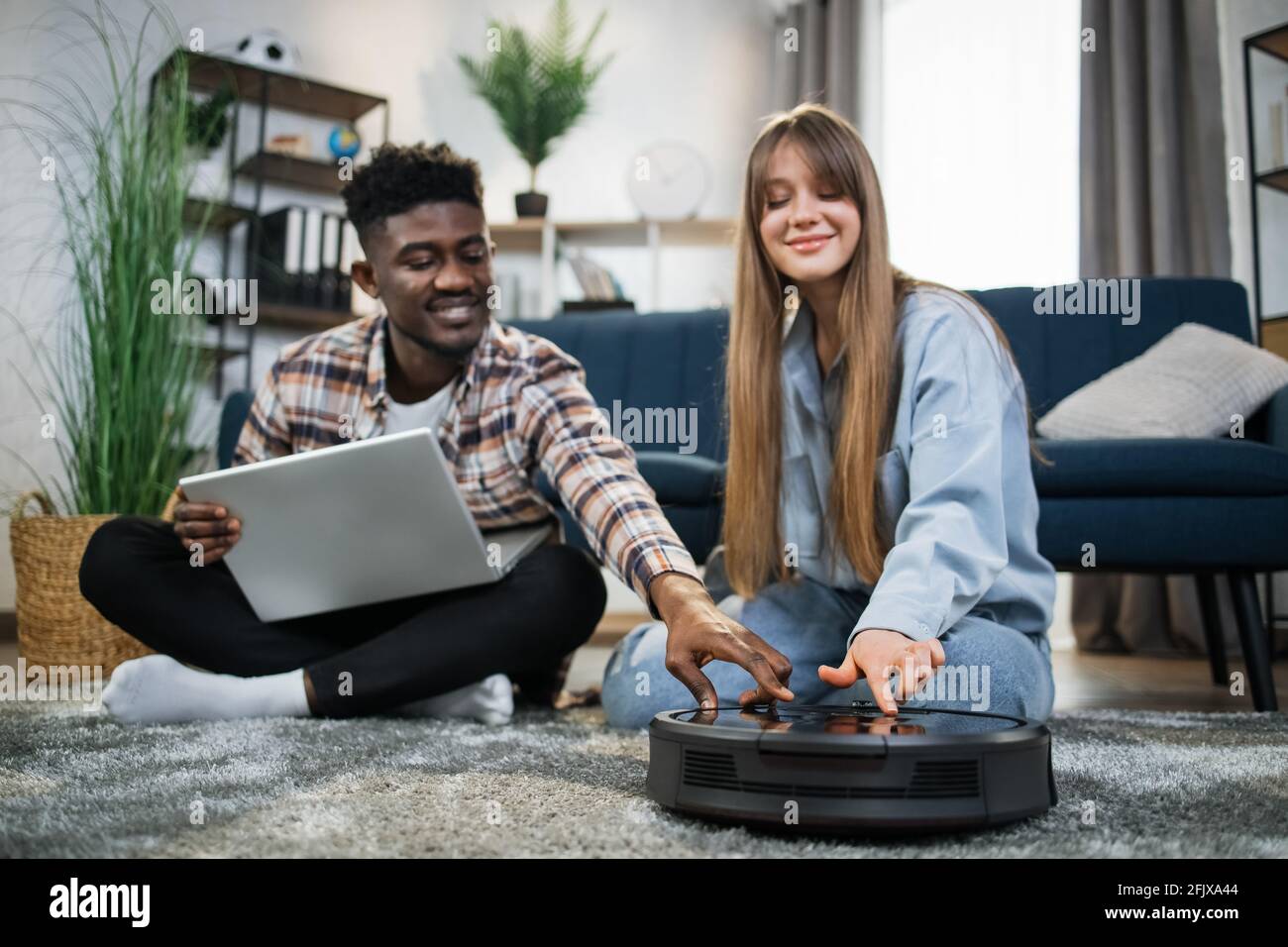 Happy international couple using wireless laptop for controlling modern ...