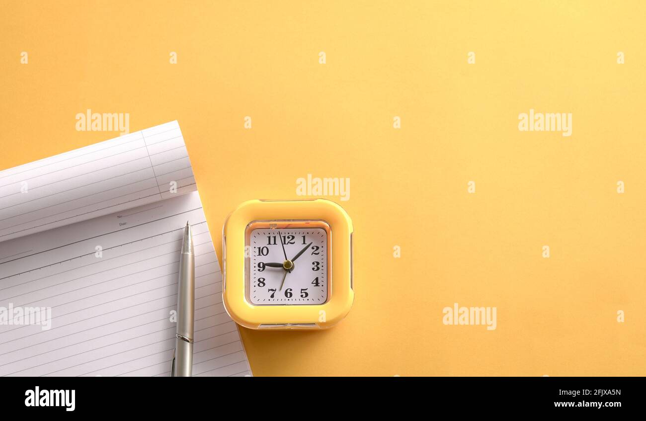 Yellow clock and writing note pad on yellow table top. Copy space Stock ...