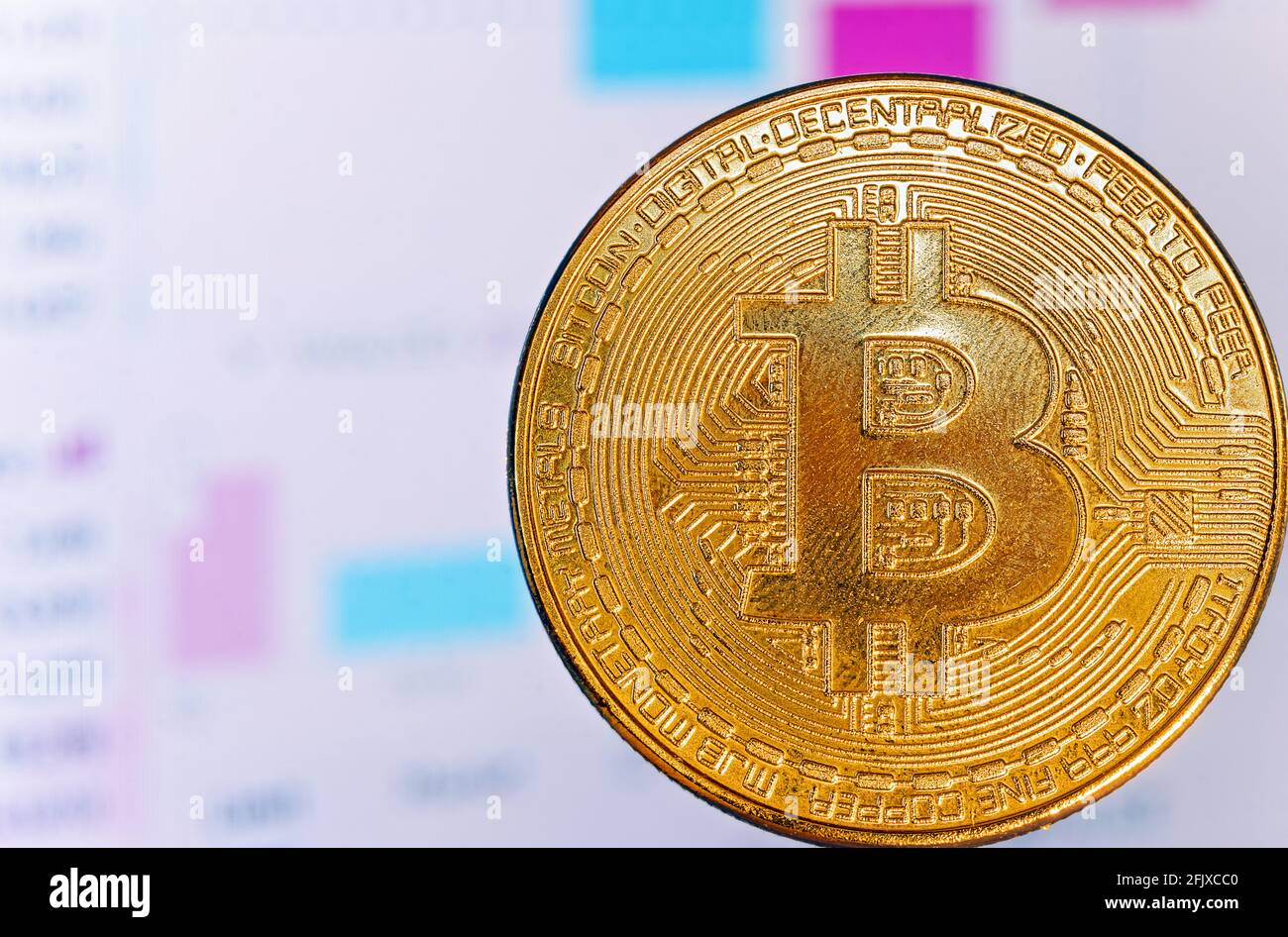 Bitcoin virtual currency in front of a screen with currency movement ...