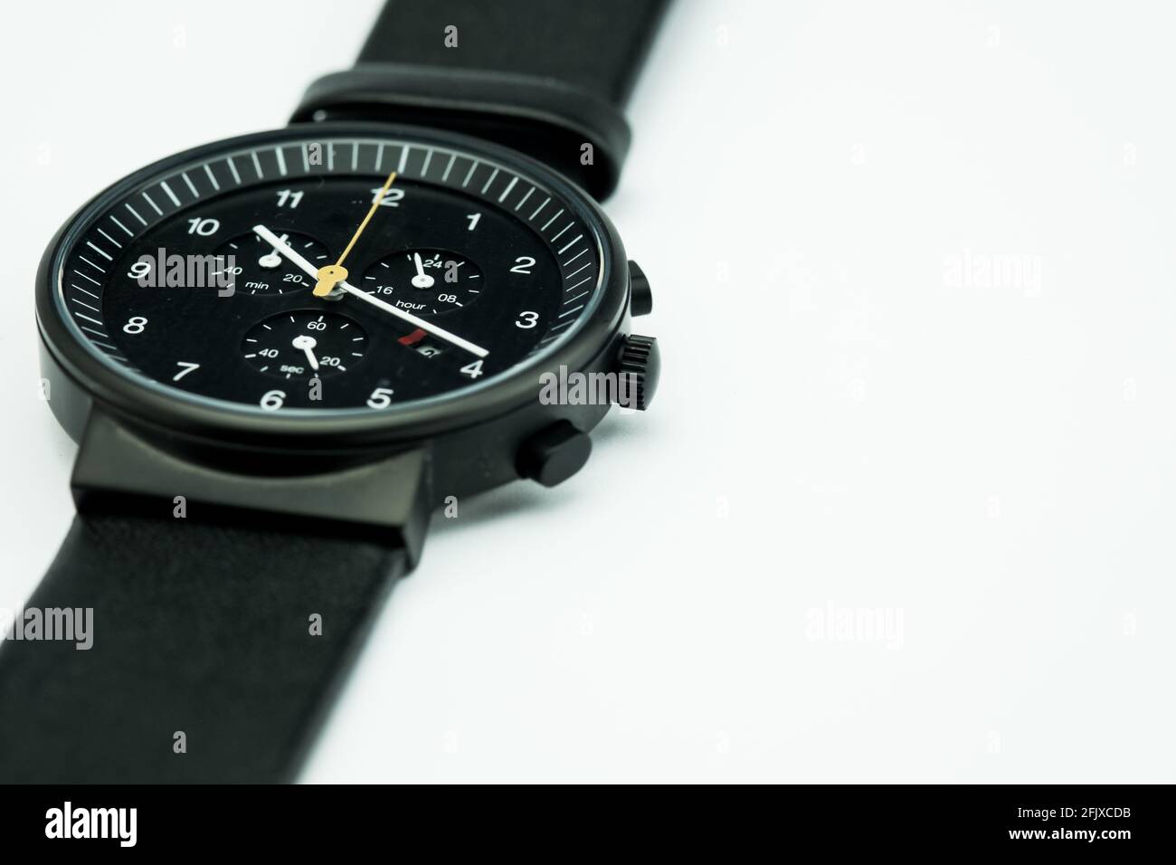 Closeup of a simple black hand watch laid flat on a plain white surface ...