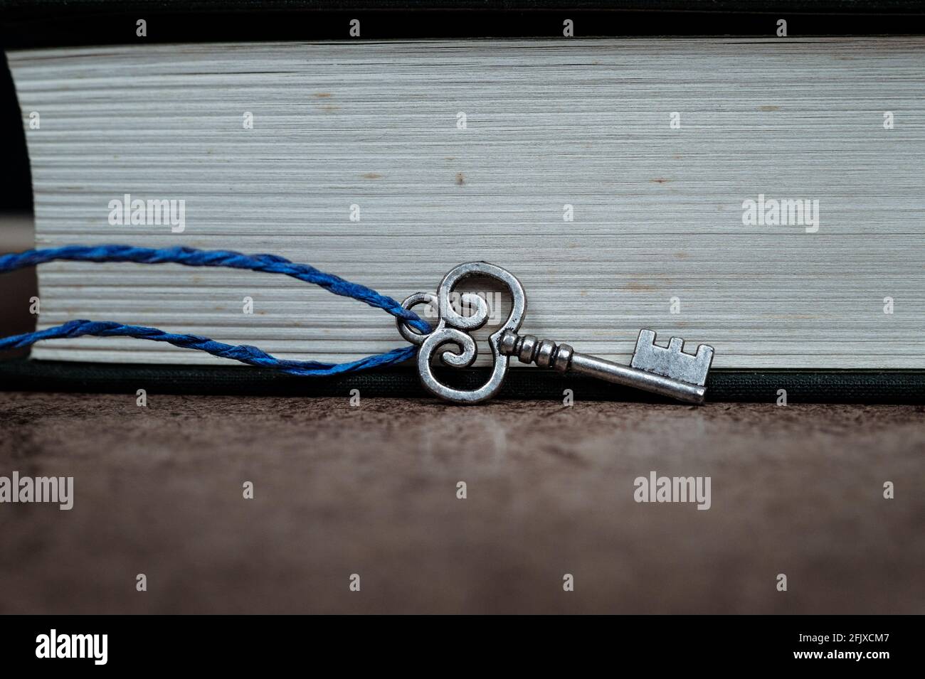 Silver key with blue string attached against closed book Stock Photo ...