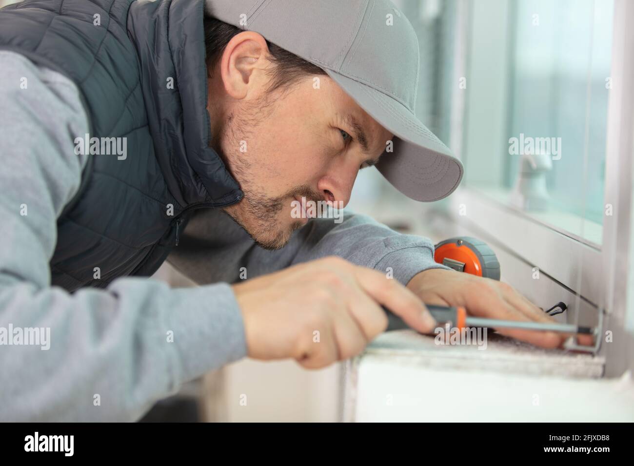 handyman using screwdriver to install a window Stock Photo - Alamy