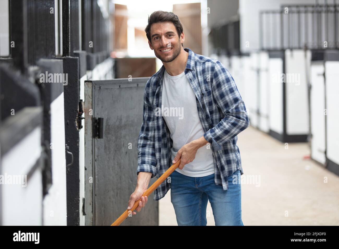 manual worker in stable cleaning and sweeping dirty stable Stock Photo ...