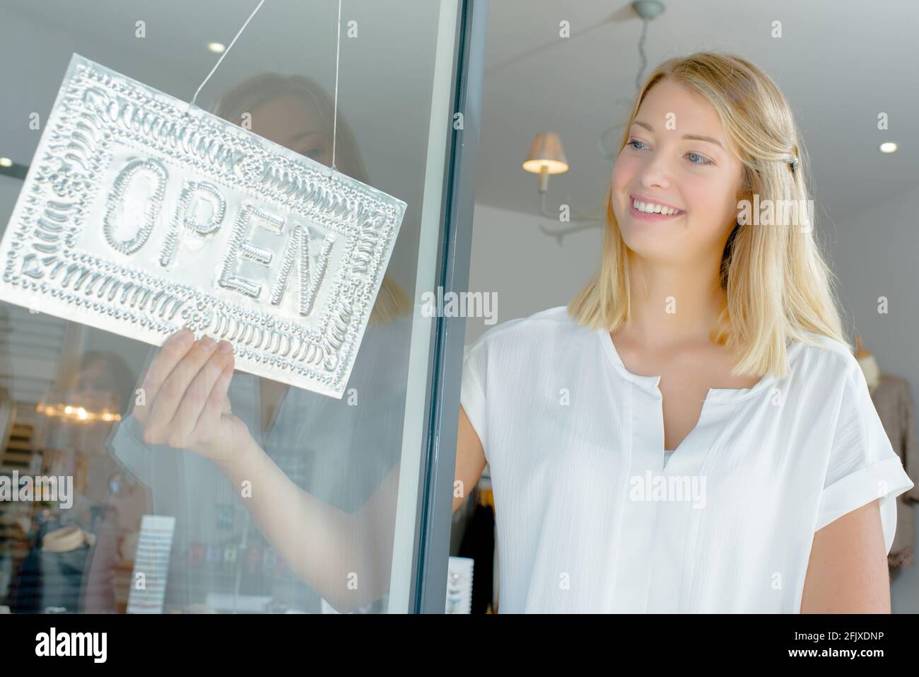 Lady holding open sign in shopfront Stock Photo - Alamy