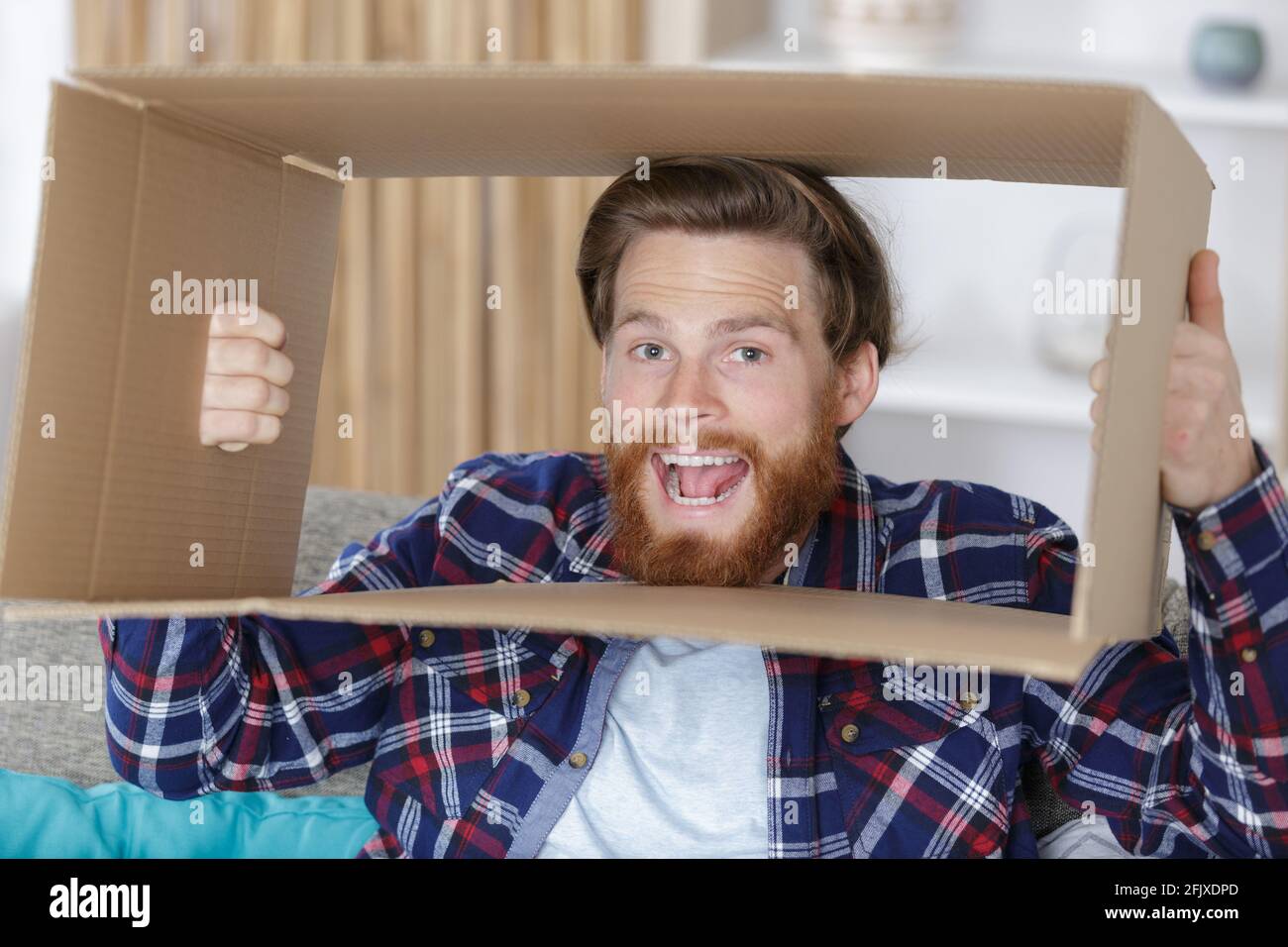 young man looking excitedly through cardboard box Stock Photo - Alamy