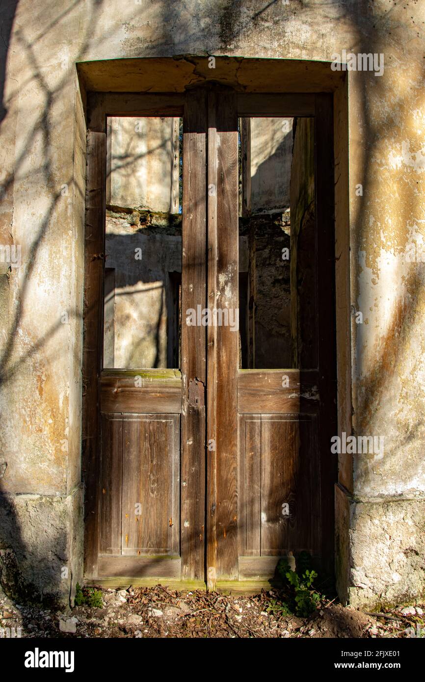 The antique damaged door in an old damaged building lit by the sun ...