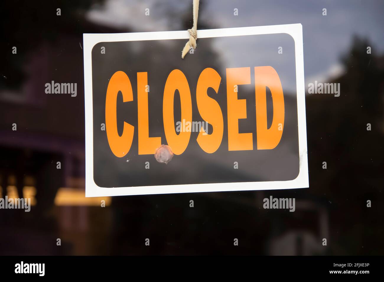 Closed sign hanging in business window by a string - crooked with glob ...