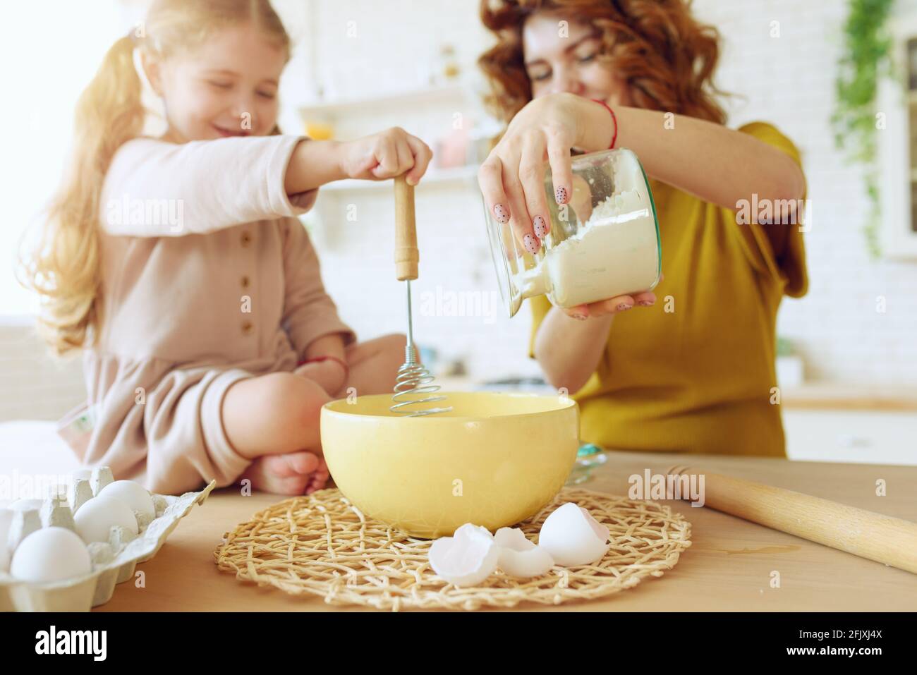 Mother and daughter prepare a cake together in the kitchen Stock Photo ...