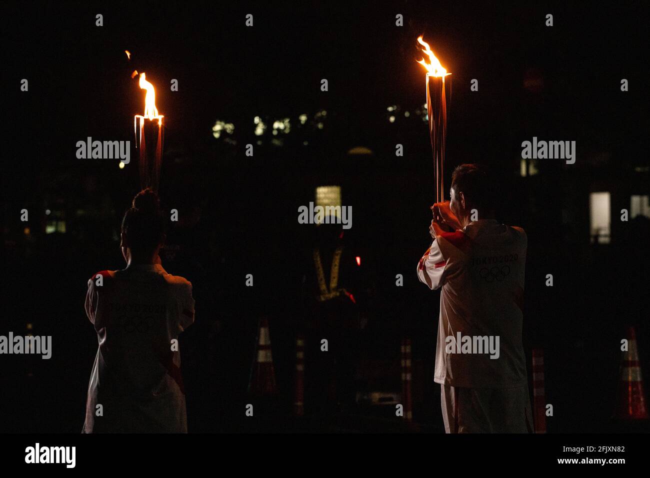 Local torchbearers pass the Olympic flame during the Tokyo 2020 Olympic ...