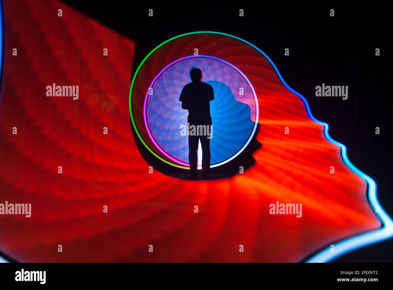One person standing alone against beautiful color circle LED light ...