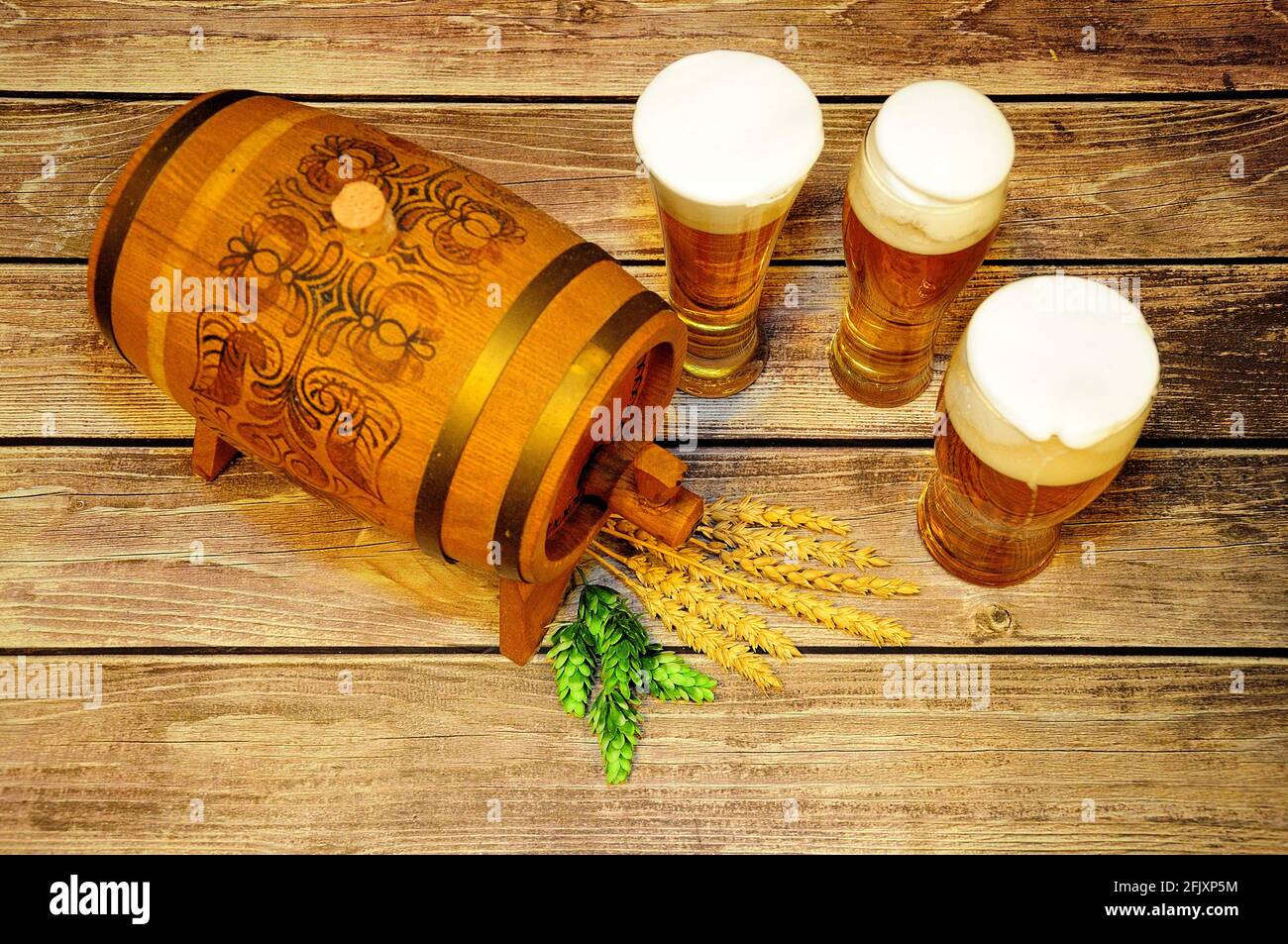 A wooden keg, hops, barley and three glasses of frothy lager beer sit ...