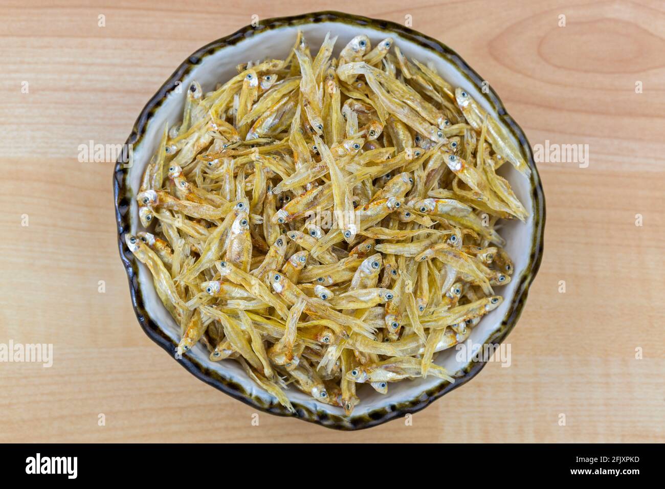 Dried Anchovy in ceramic bowl. Anchovies small fish, top view of wooden ...