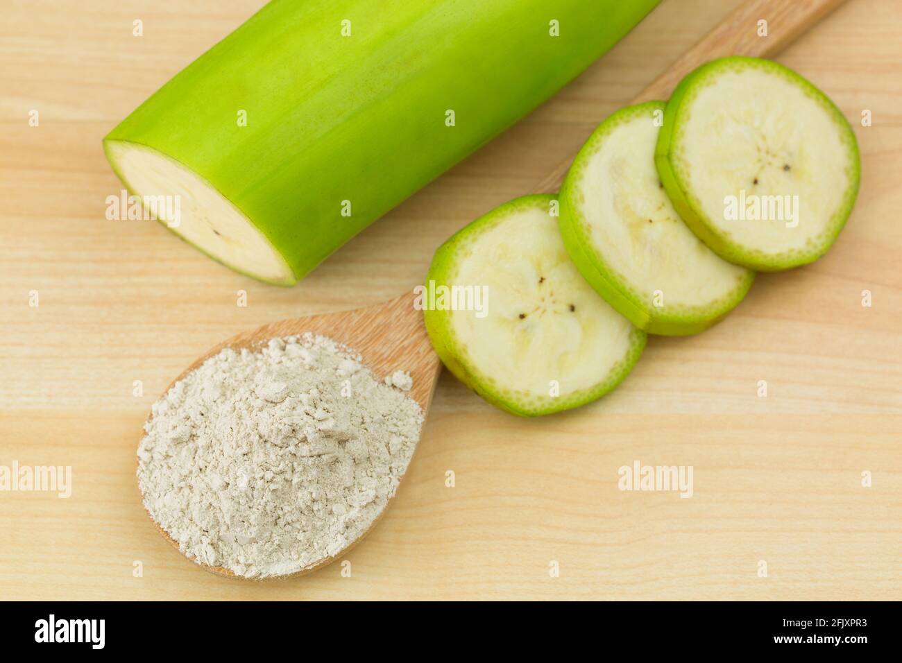 Synbiotic dried banana powder next to sliced fruit of organic whole ...