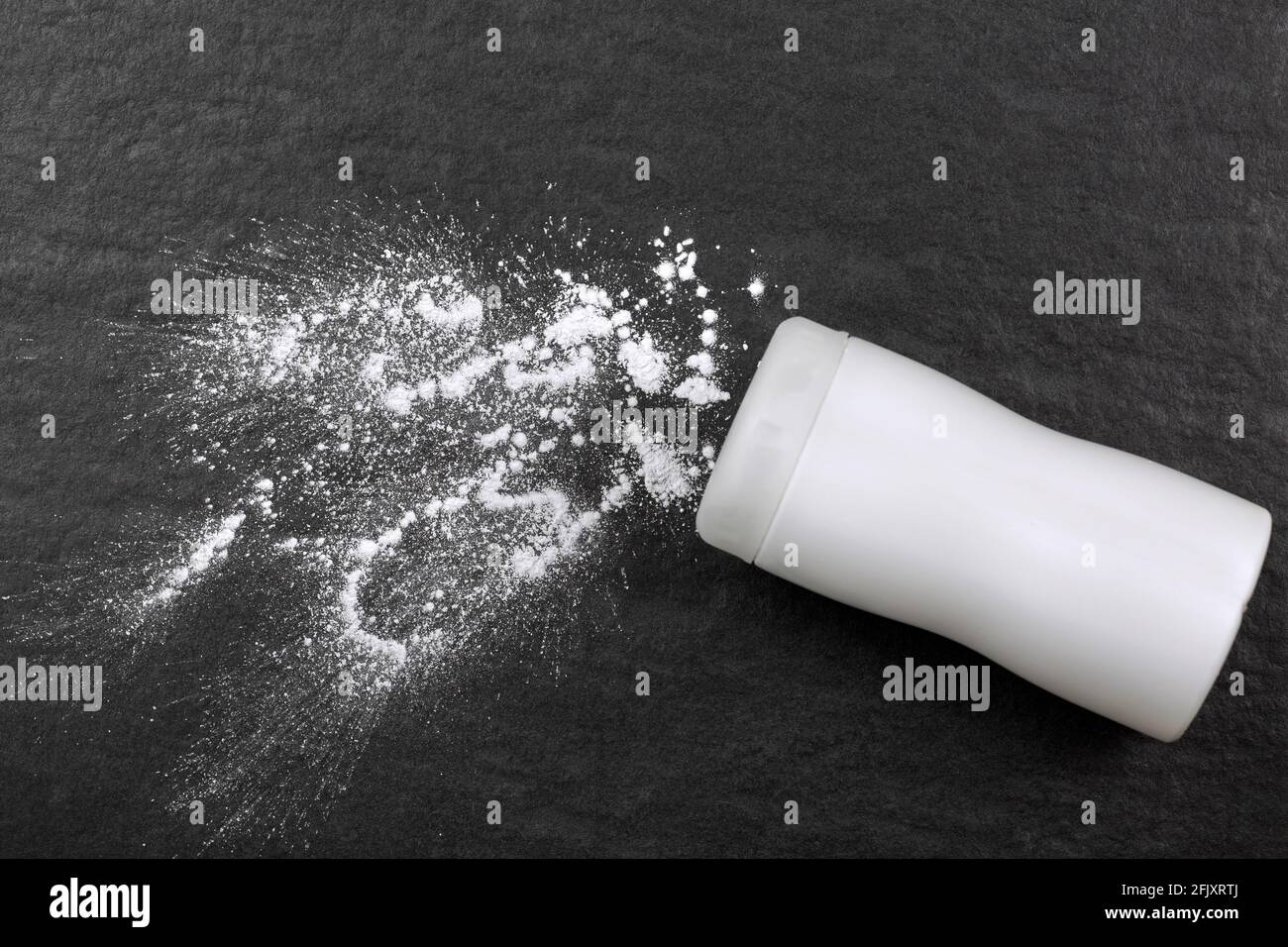 Bottle of Talcum baby powder on dark stone background. Powder spilled ...