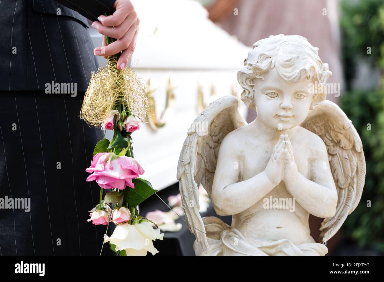 Mourning woman on funeral with pink rose standing at casket or coffin ...
