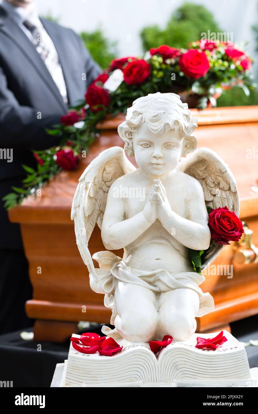Mourning man on funeral with red rose standing at casket or coffin ...