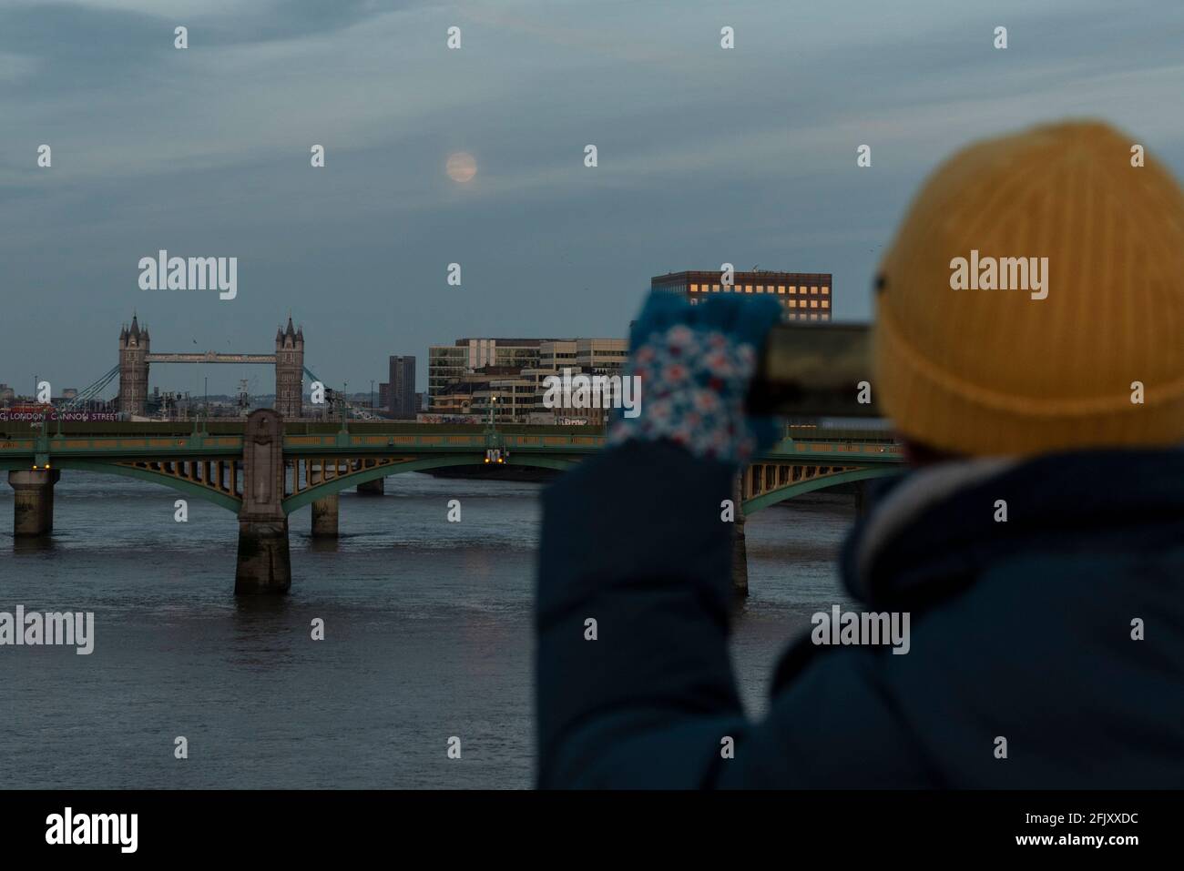 London, Britain. 26th Apr, 2021. A woman photographs the full moon ...