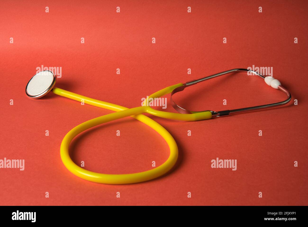 Yellow stethoscope isolated on a red background Stock Photo - Alamy